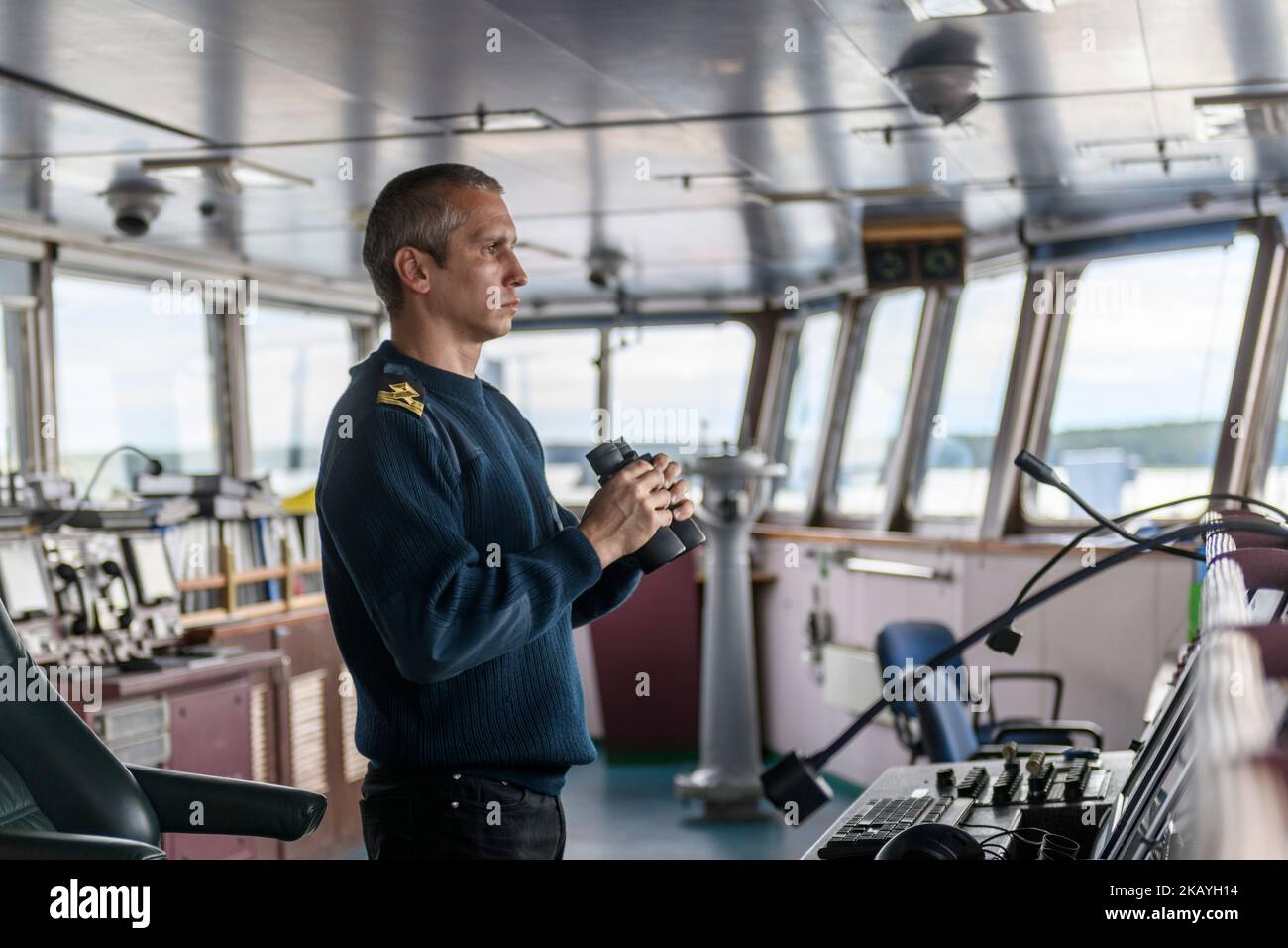 Deck officer with binoculars on navigational bridge. Seaman on board of ...