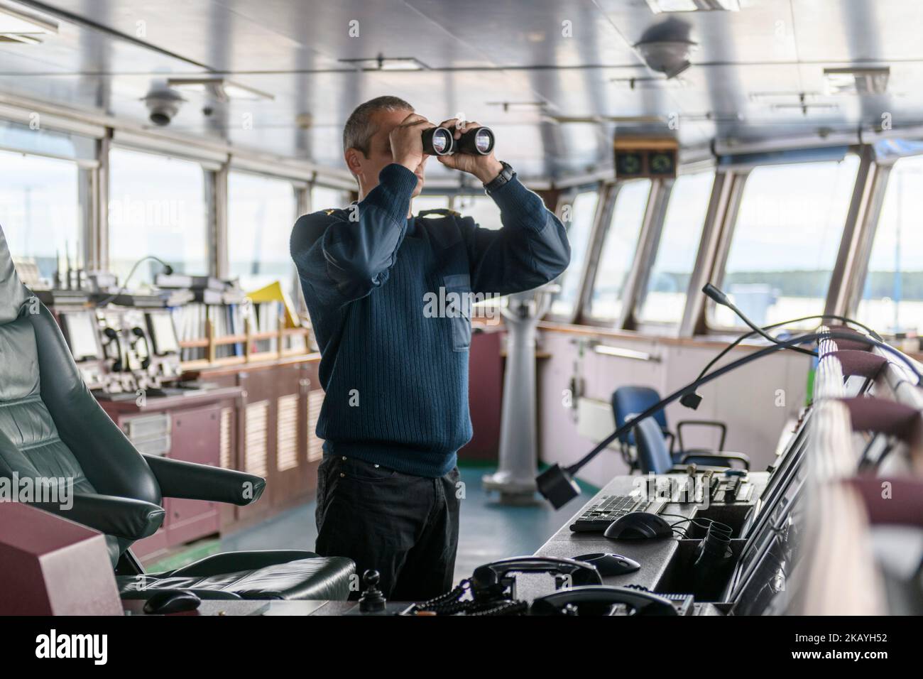 Deck officer with binoculars on navigational bridge. Seaman on board of ...