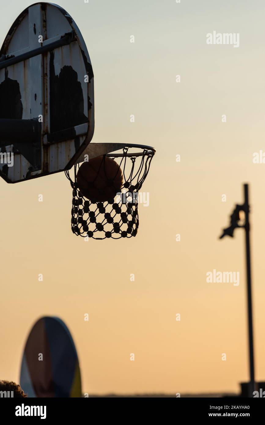 Basketball through hoop in golden sunset light Stock Photo - Alamy