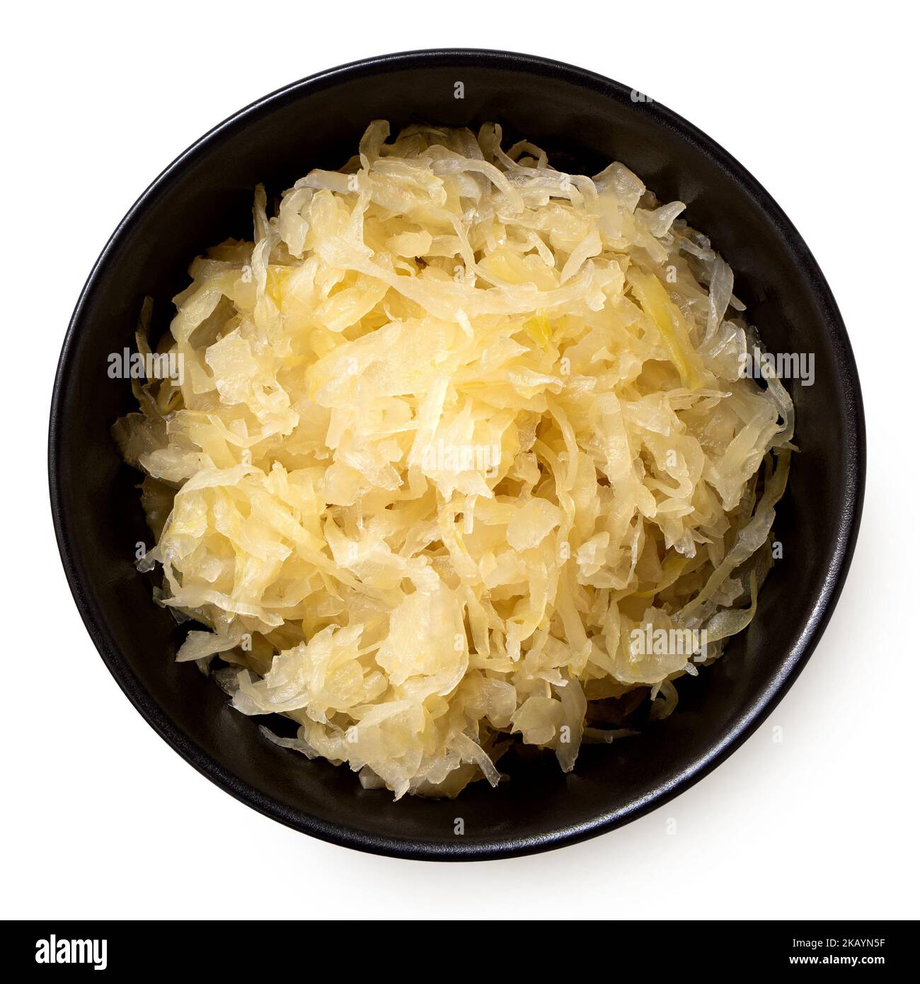 Fermented white cabbage in a black ceramic bowl isolated on white. Top ...