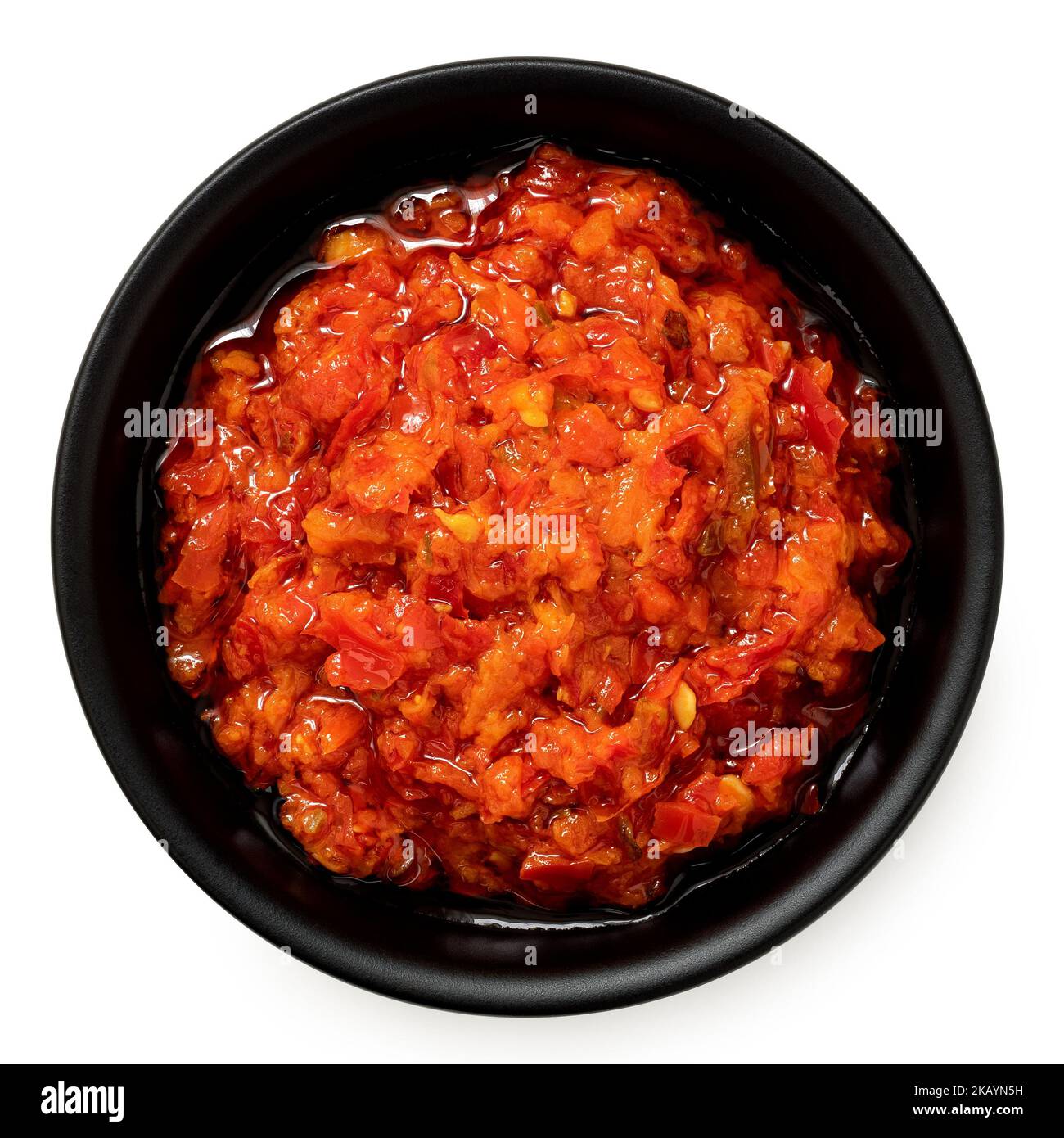 Chopped red chilli peppers in olive oil in black ceramic bowl isolated ...