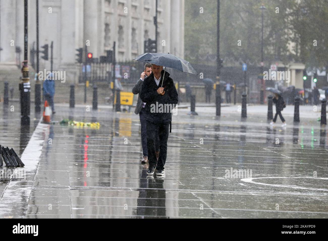 A man shelters under an umbrella during rainfall in London. According ...
