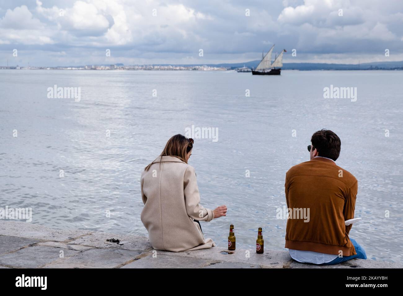 COUPLE, BEERS, OLD BOAT: An antique boat passes tourists on the Tejo ...