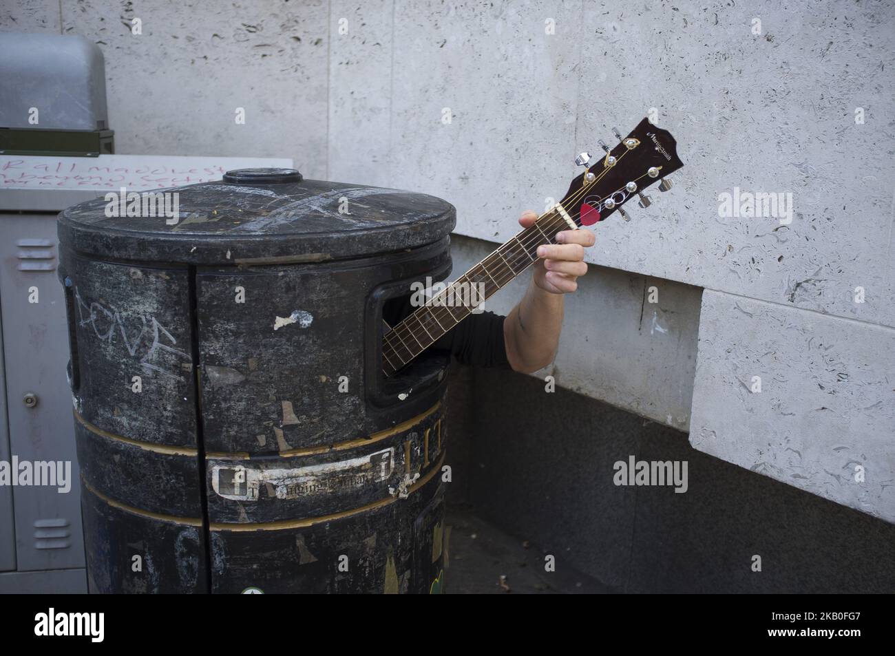 A busker is pictured as he plays guitar into a garbage bin in Cambridge ...