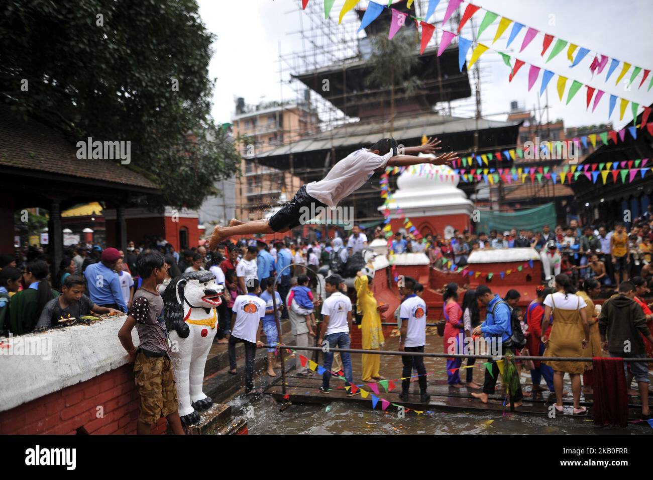 A Nepalese youth somersault on the water collected in Kumbheshwor ...