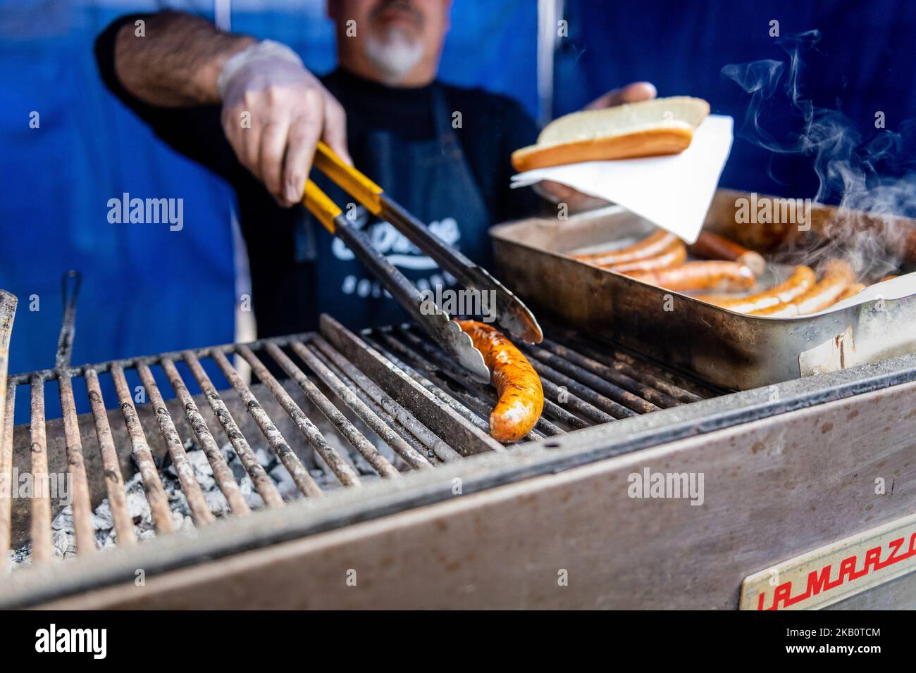 Chef cooking sausages, hotdogs on a griddle, barbecue, Rolling hand ...
