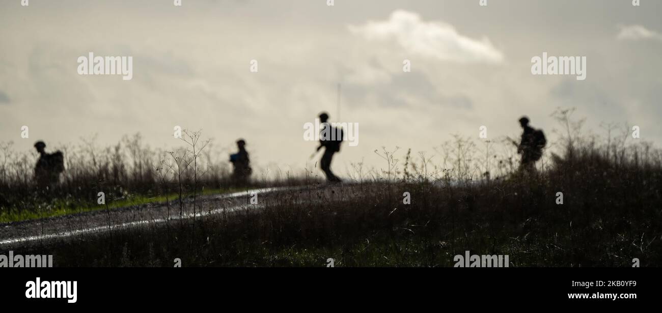 silhouetted British army soldiers on a military training exercise in open countryside, Wiltshire ...