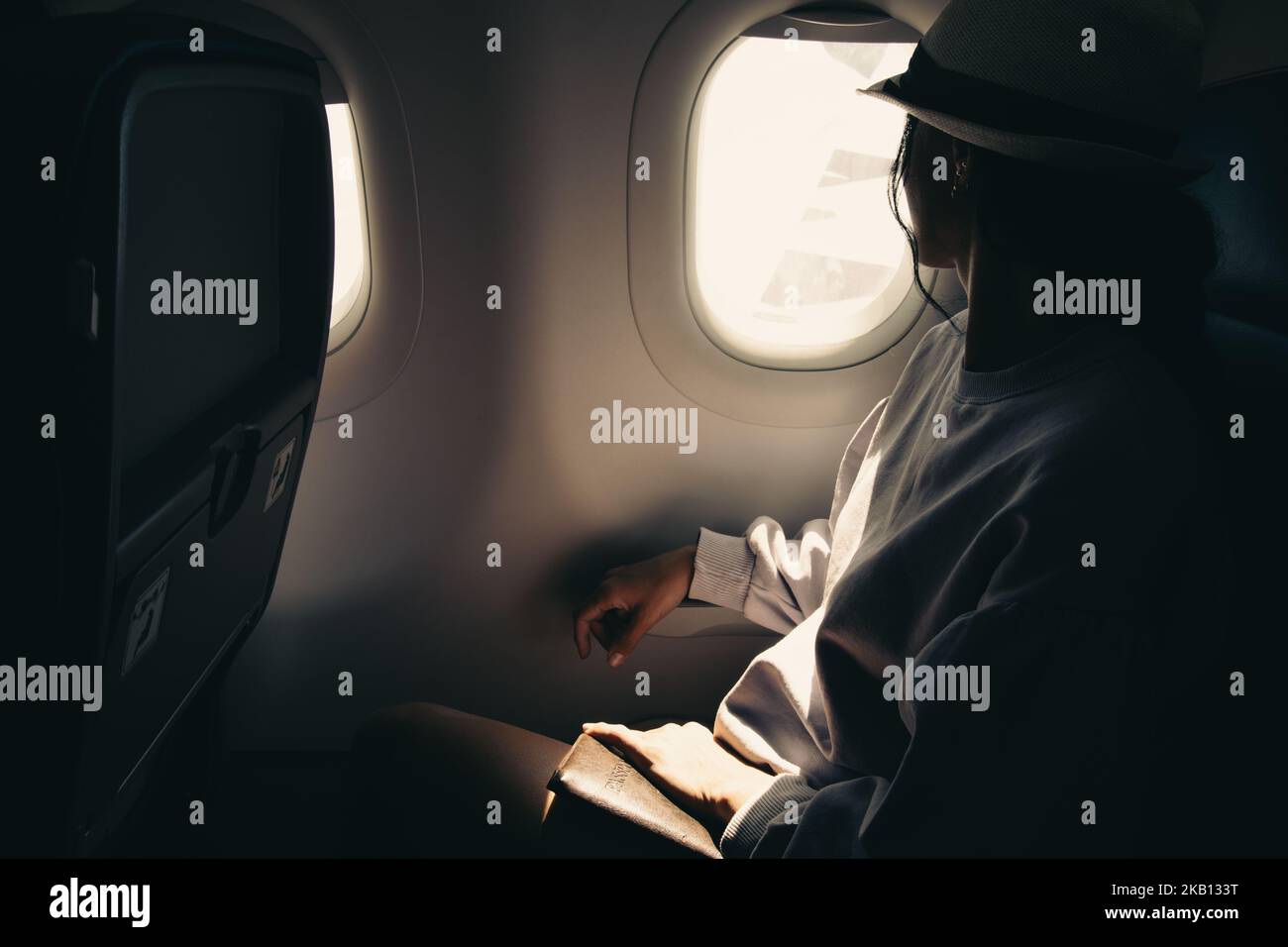 Young traveller woman sitting inside plane on flight watch to sky and ...