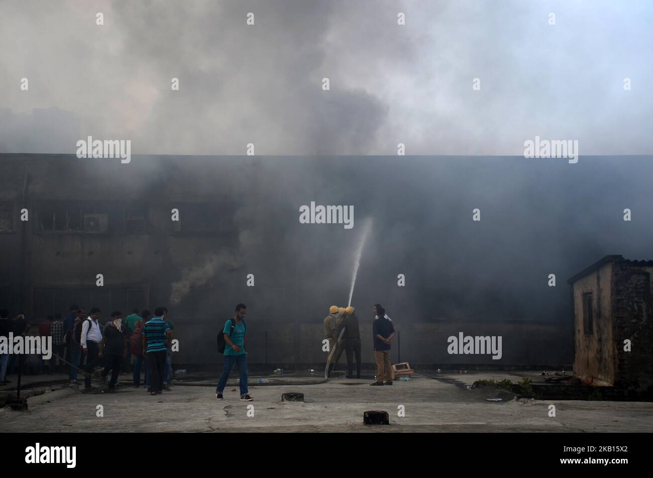 Indian fire fighters spray water from the outside of an adjacent ...