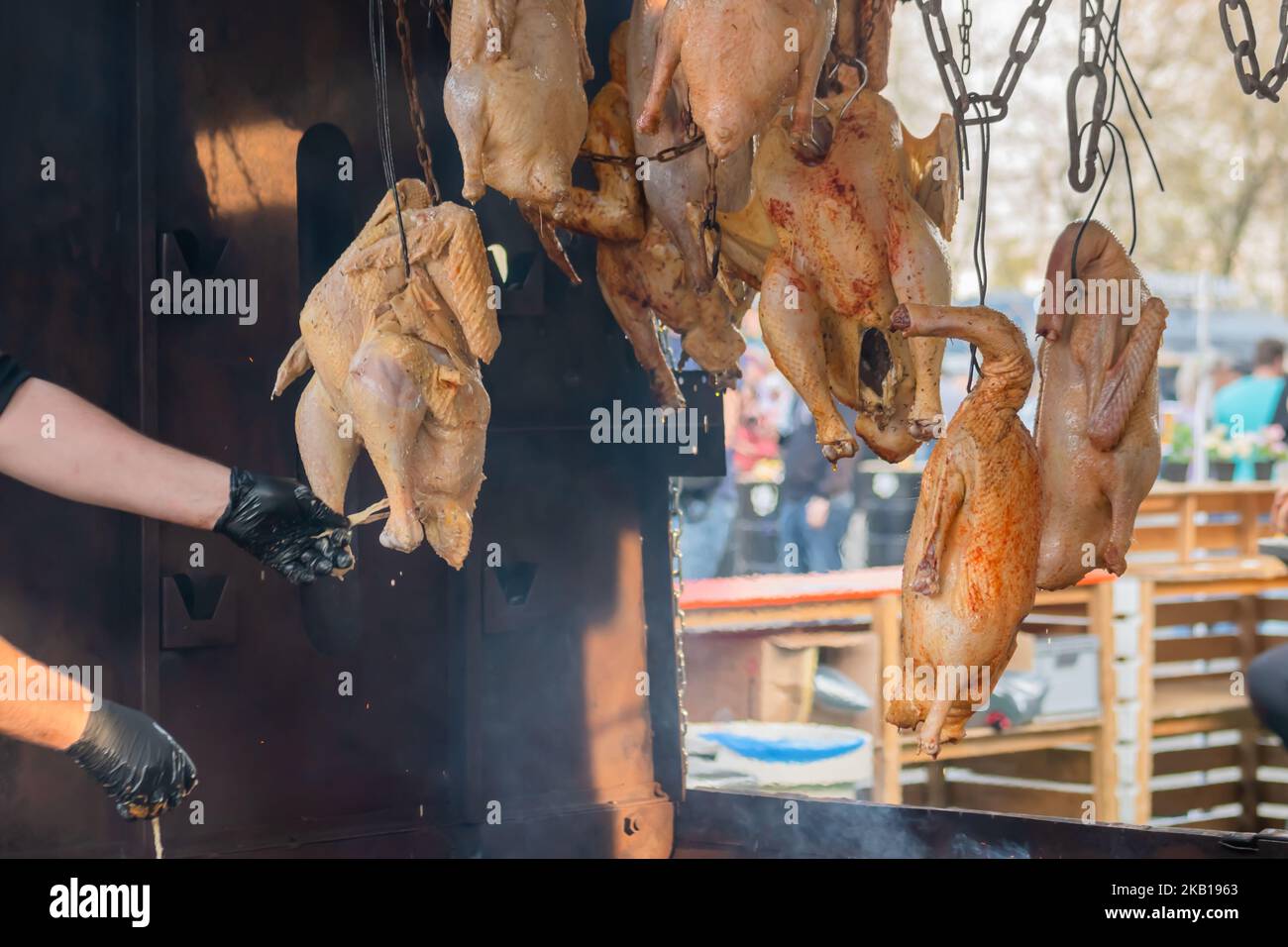 Hanging whole chickens smoking over coals at summer food market Stock ...