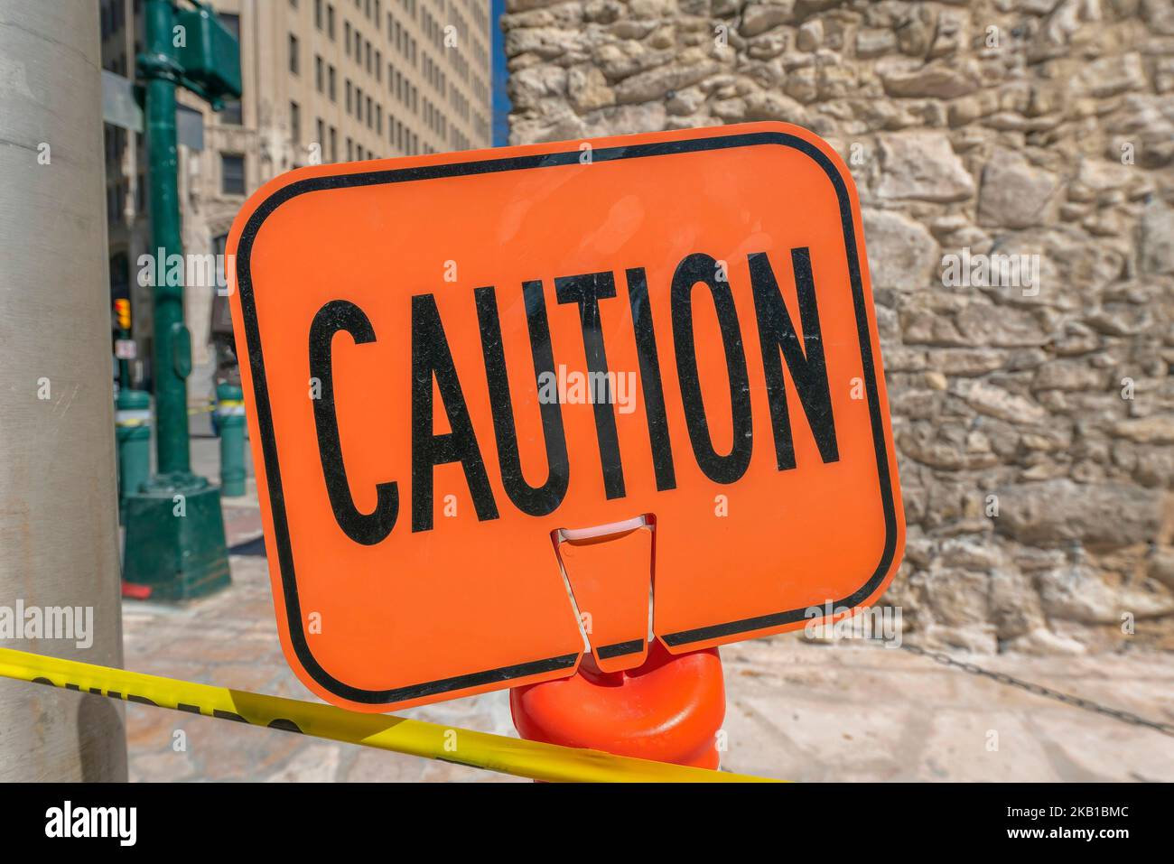 Bright orange Caution sign and yellow tape with stone brick wall ...