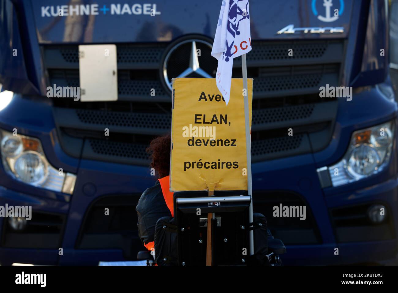 A woman in a wheelchair blocls a truck during the protest. The placard ...