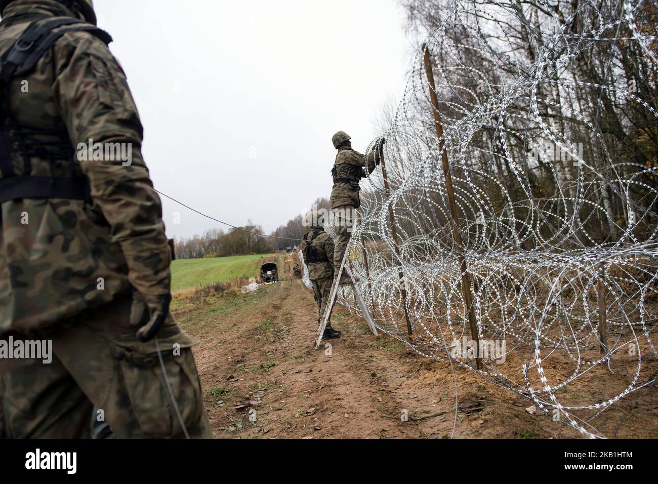 Polish soldiers are building a razor wire fence along the border with ...