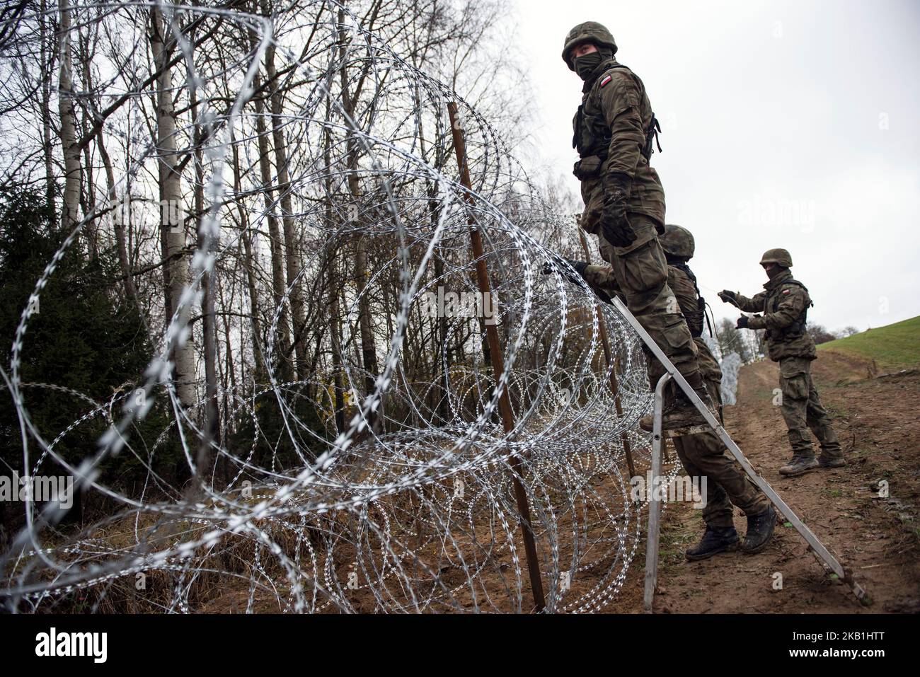 Polish soldiers are building a razor wire fence along the border with ...