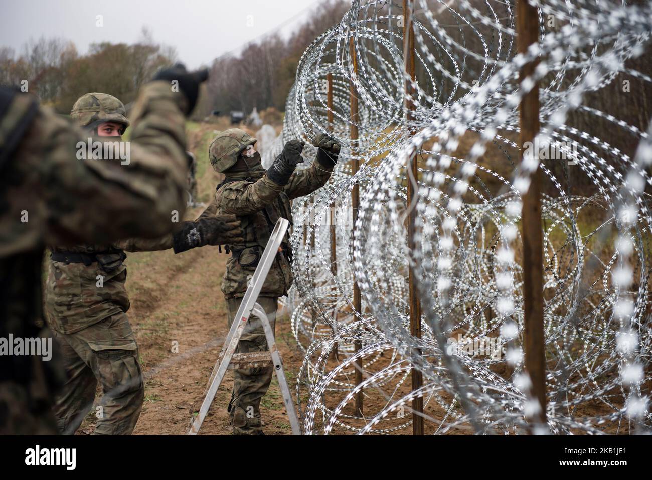 Polish soldiers are building a razor wire fence along the border with ...
