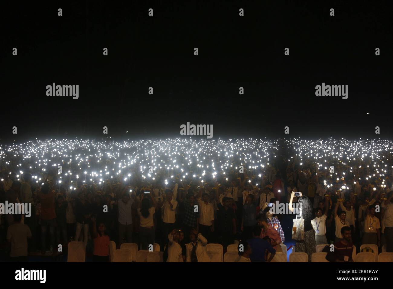 Women takes a picture of students who hold up solar lamps as they break ...