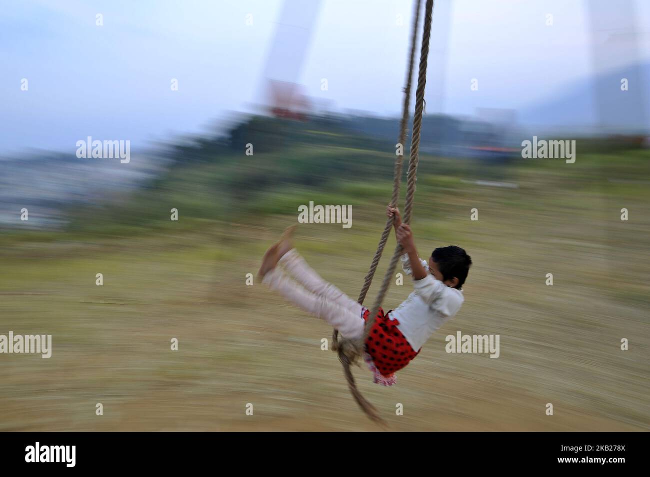 A Little girl playing on a traditional bamboo ping or swing during ...