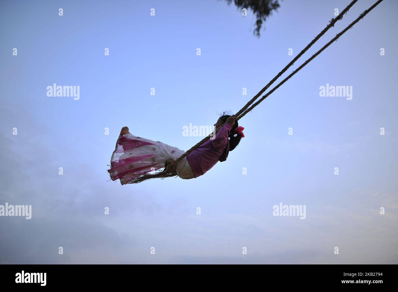 A Little girl playing on a traditional bamboo ping or swing during ...