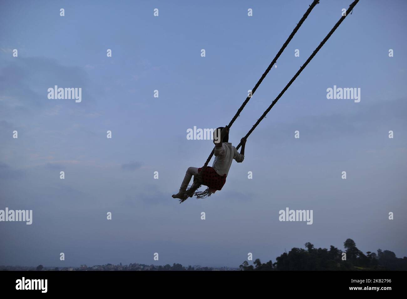 A Little girl playing on a traditional bamboo ping or swing during ...