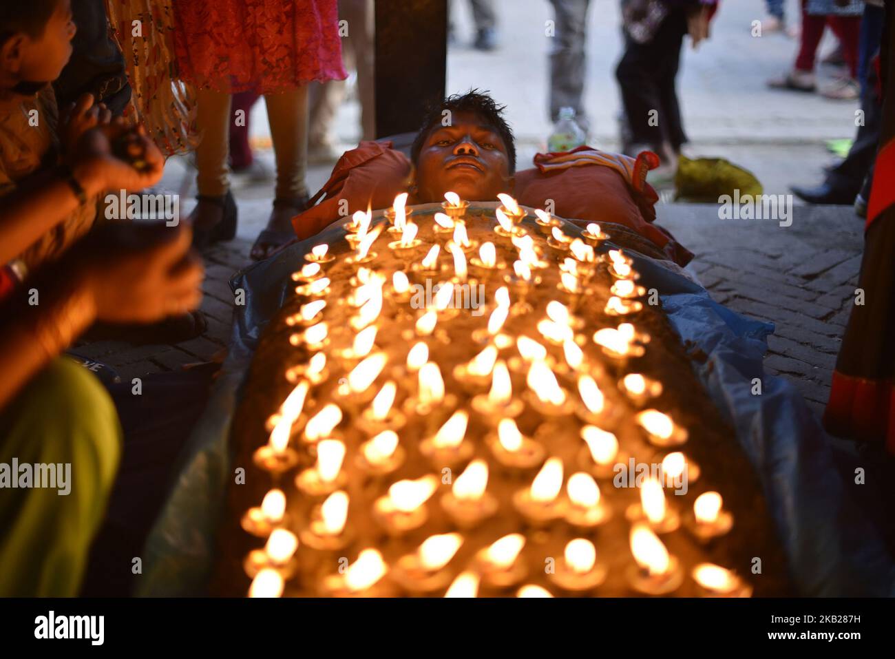 A Nepalese devotee hold oil lamps on their body during the tenth day of ...