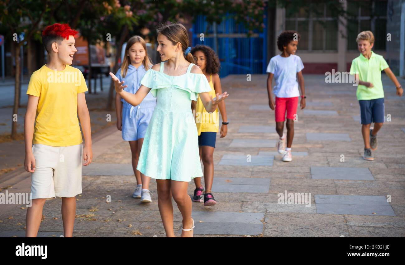 Happy tweens girl and boy talking while walking around city Stock Photo ...
