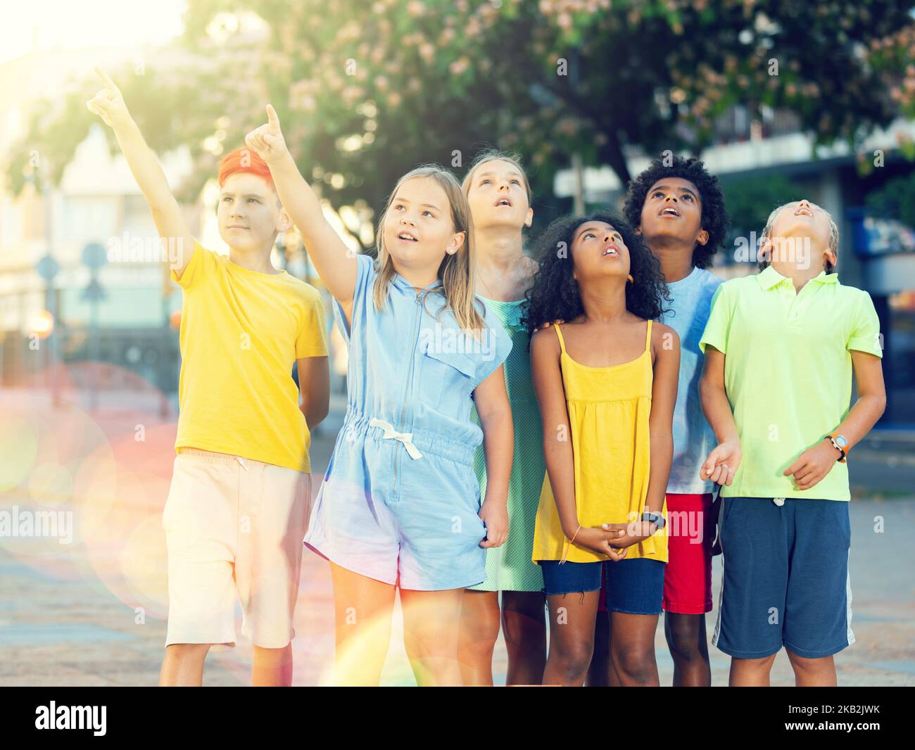 Happy inquiring preteen friends looking with interest at something and ...