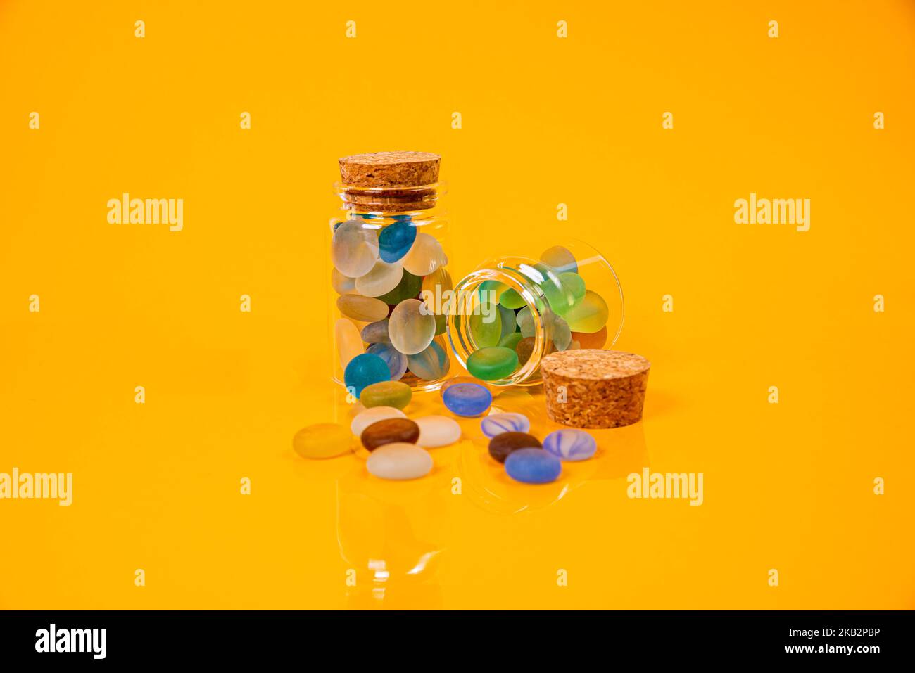 colored stones in glass in jar in bucket on orange background isolated ...