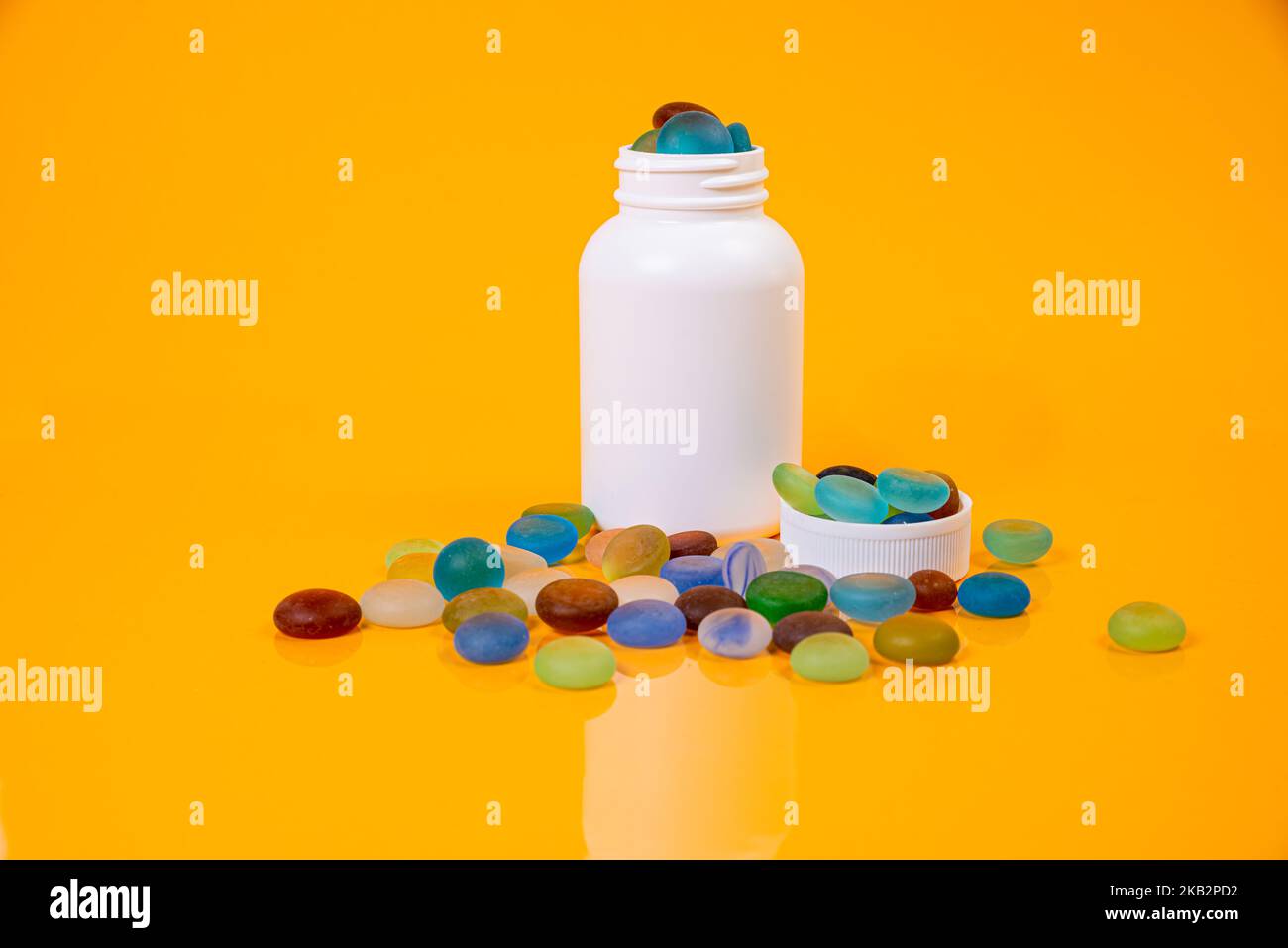colored stones in glass in jar in bucket on orange background isolated ...
