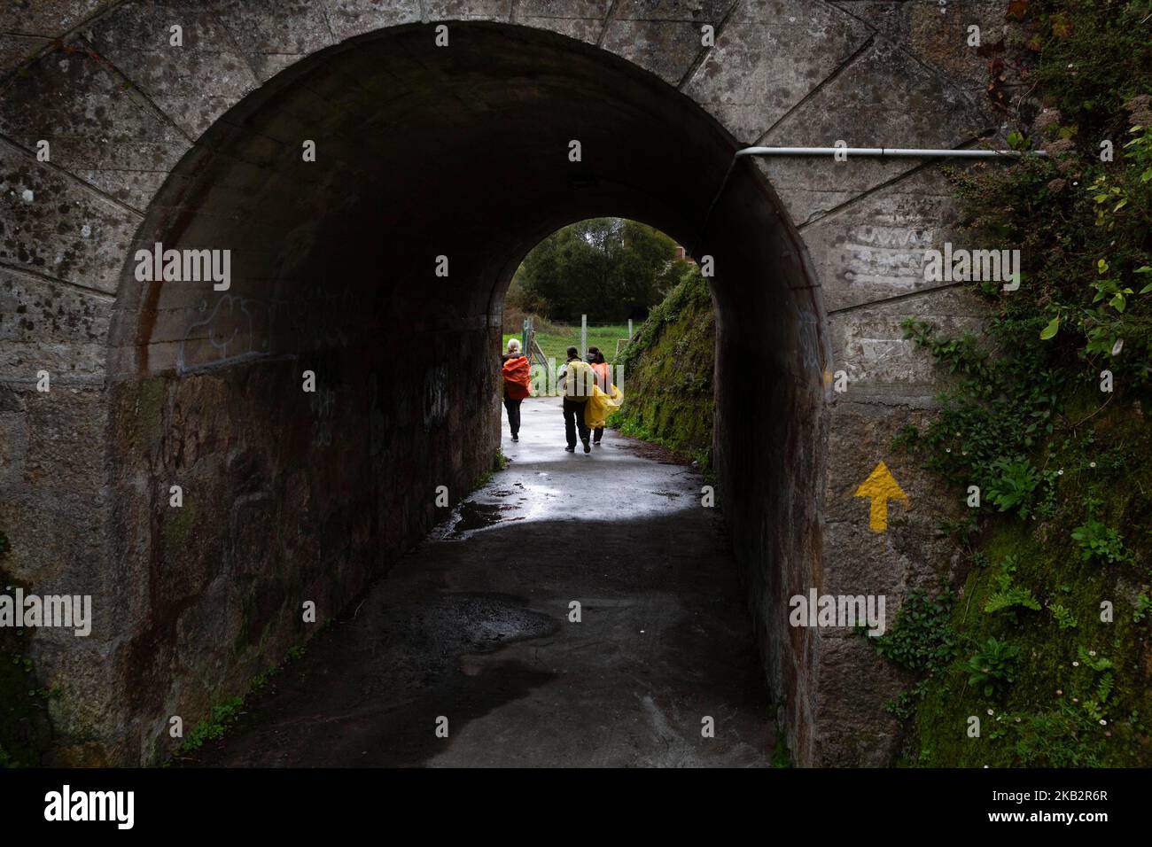 Three pilgrims cross a tunnel in Pontecesures on the Portuguese Camino ...