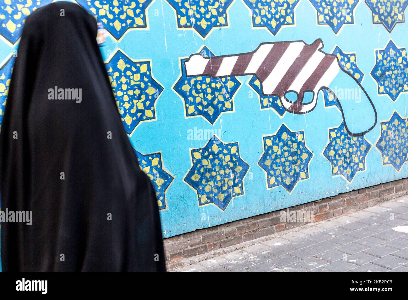 A woman walks in front of revolutionary graffiti on Taleqani Street in ...