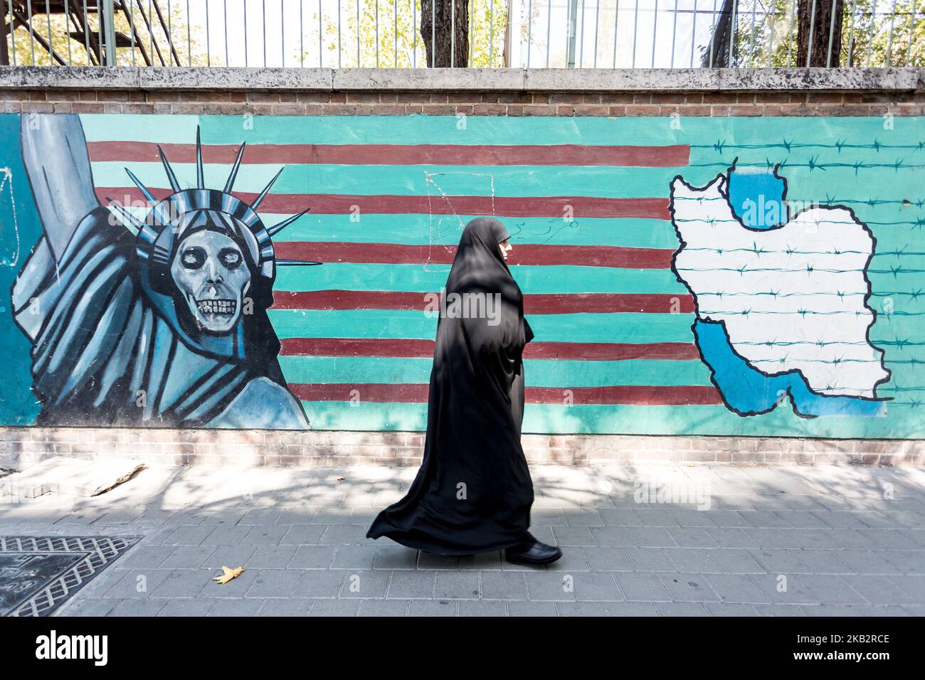 A woman walks in front of anti-American revolutionary graffiti on ...