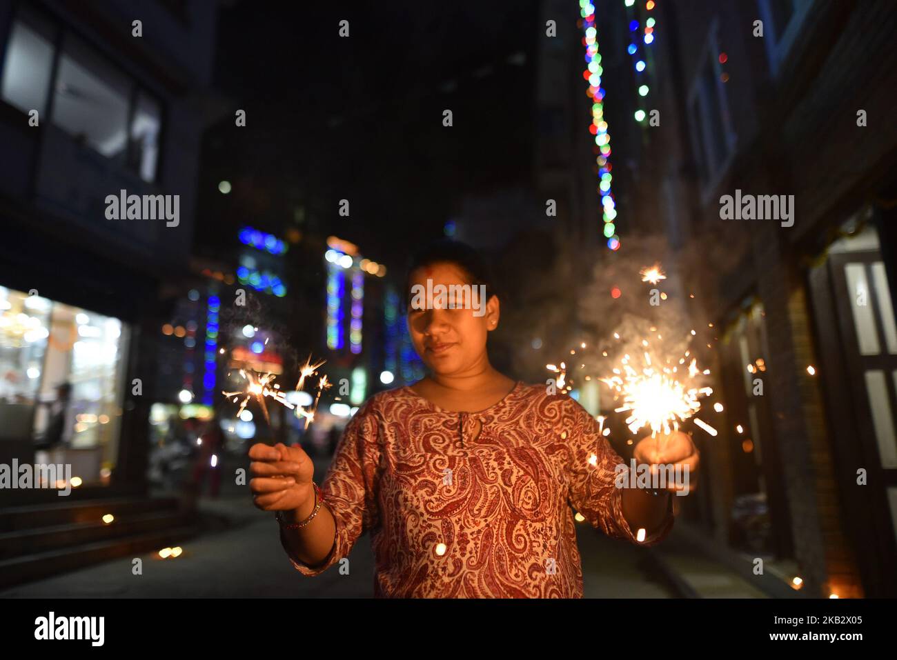 A girl smiles as holding beautiful sparklers (fire crackers) in hands ...