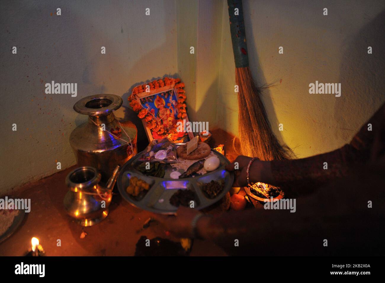 A Nepalese devotee offering ritual prayer towards a poster of Laxmi ...