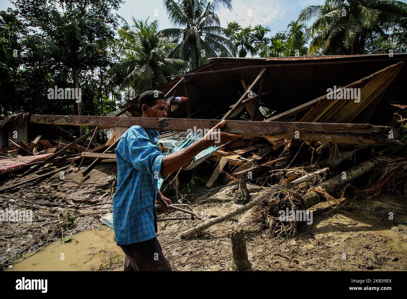 A man collects debris from a house damaged after a flood caused by ...