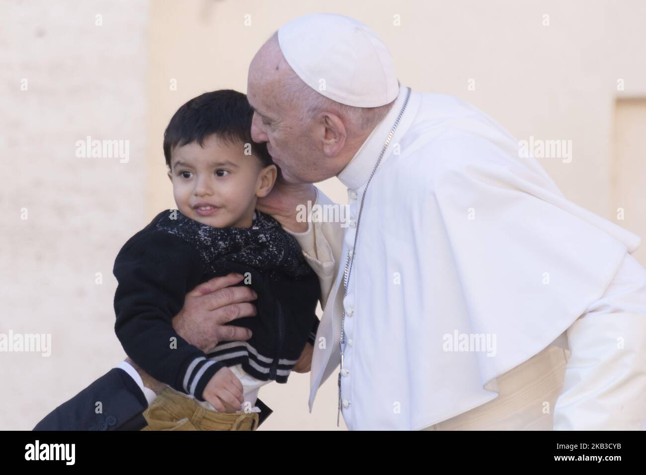 Pope Francis kisses a child as he arrives for his weekly general ...