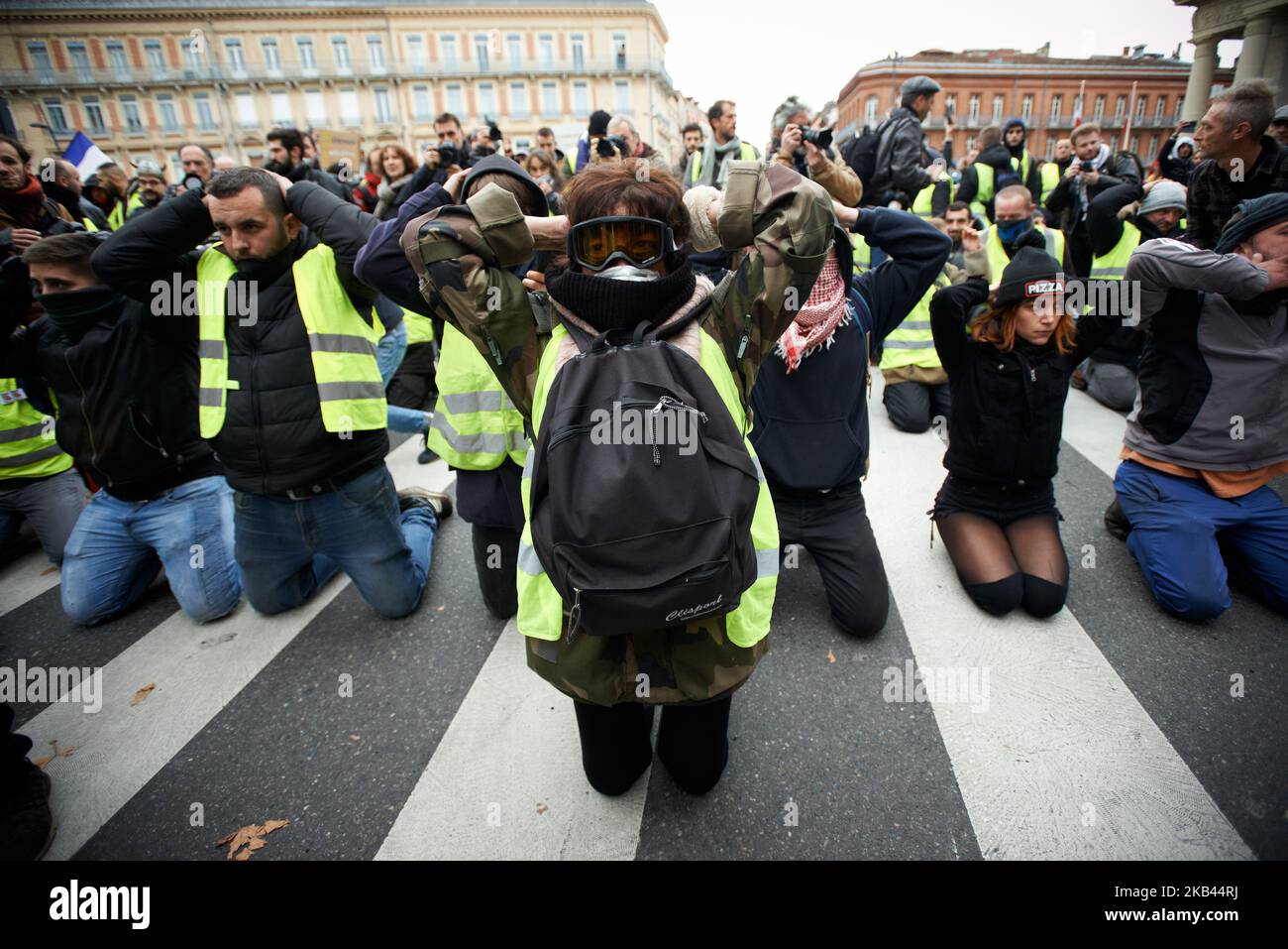 People stay on their knees with their hands on their head in a ...