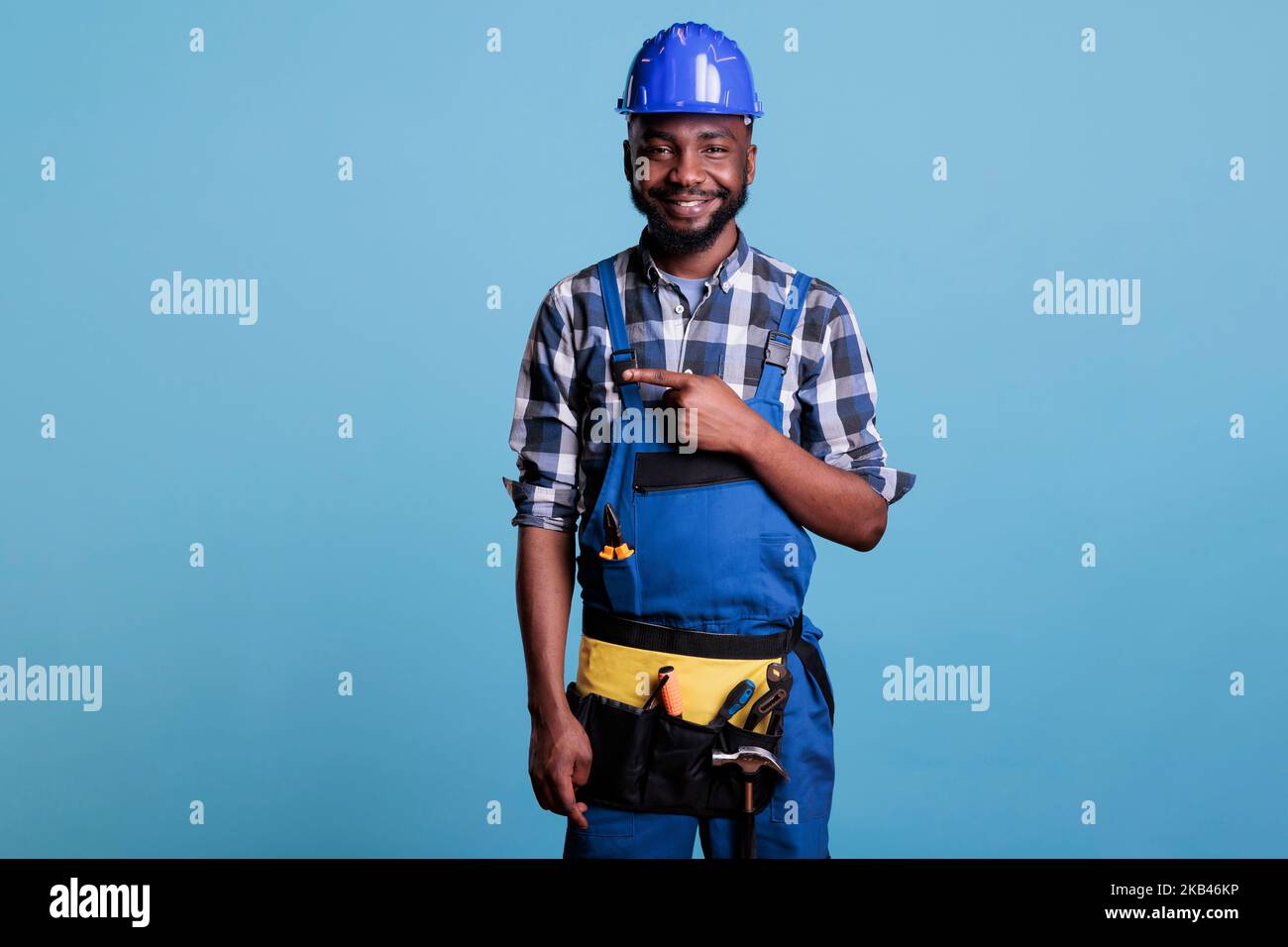 Portrait of contractor in hard hat looking happy while pointing his ...