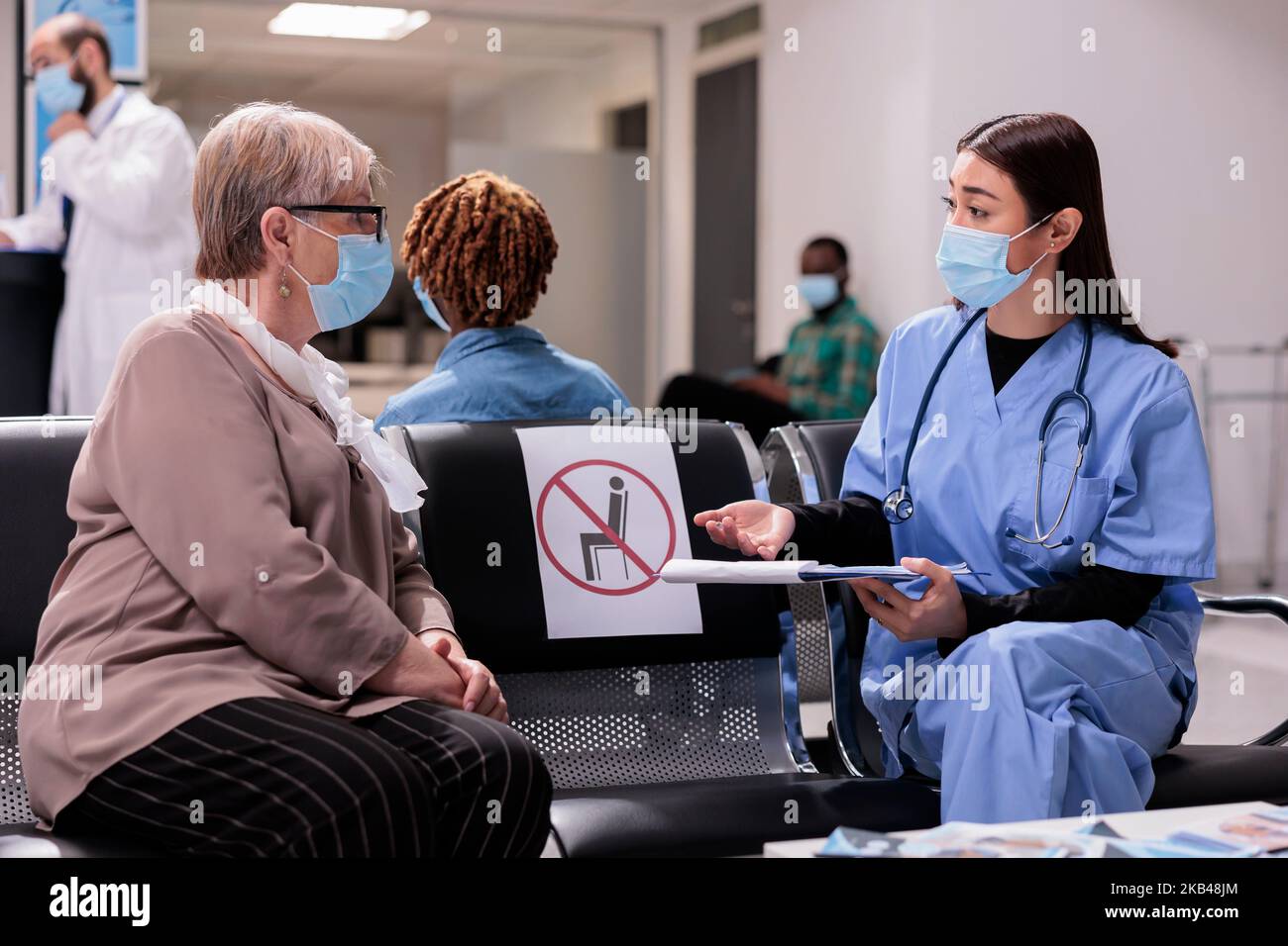 Medical personnel studying health status of elderly female patient ...