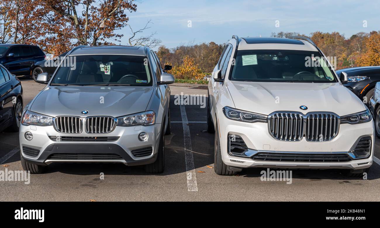 Two BMW sedans, one white and the other silver for sale at a dealership ...