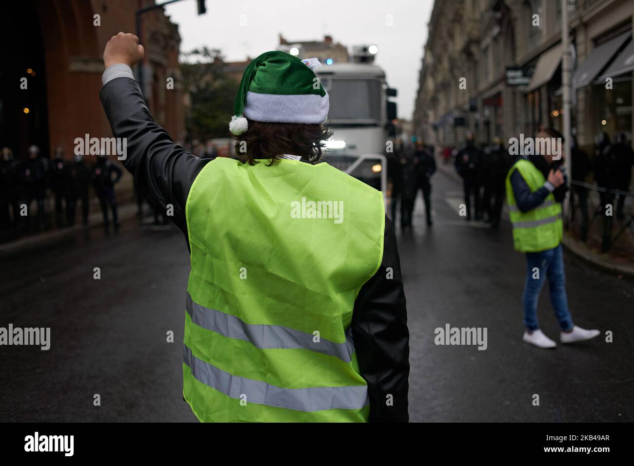 A Yellow Vest rises his fist in front of riot police and its water ...