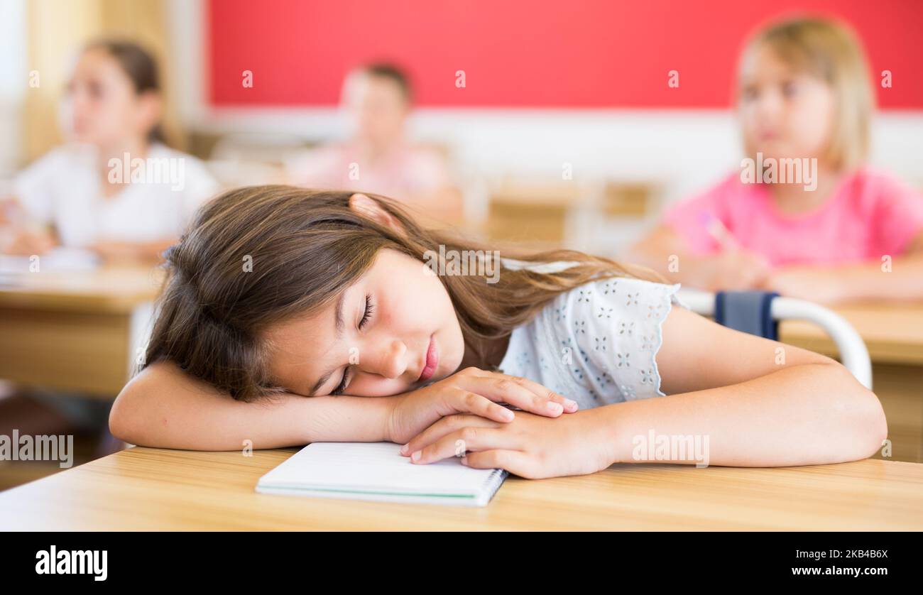 Tired school girl sleeping at desk in classroom Stock Photo - Alamy