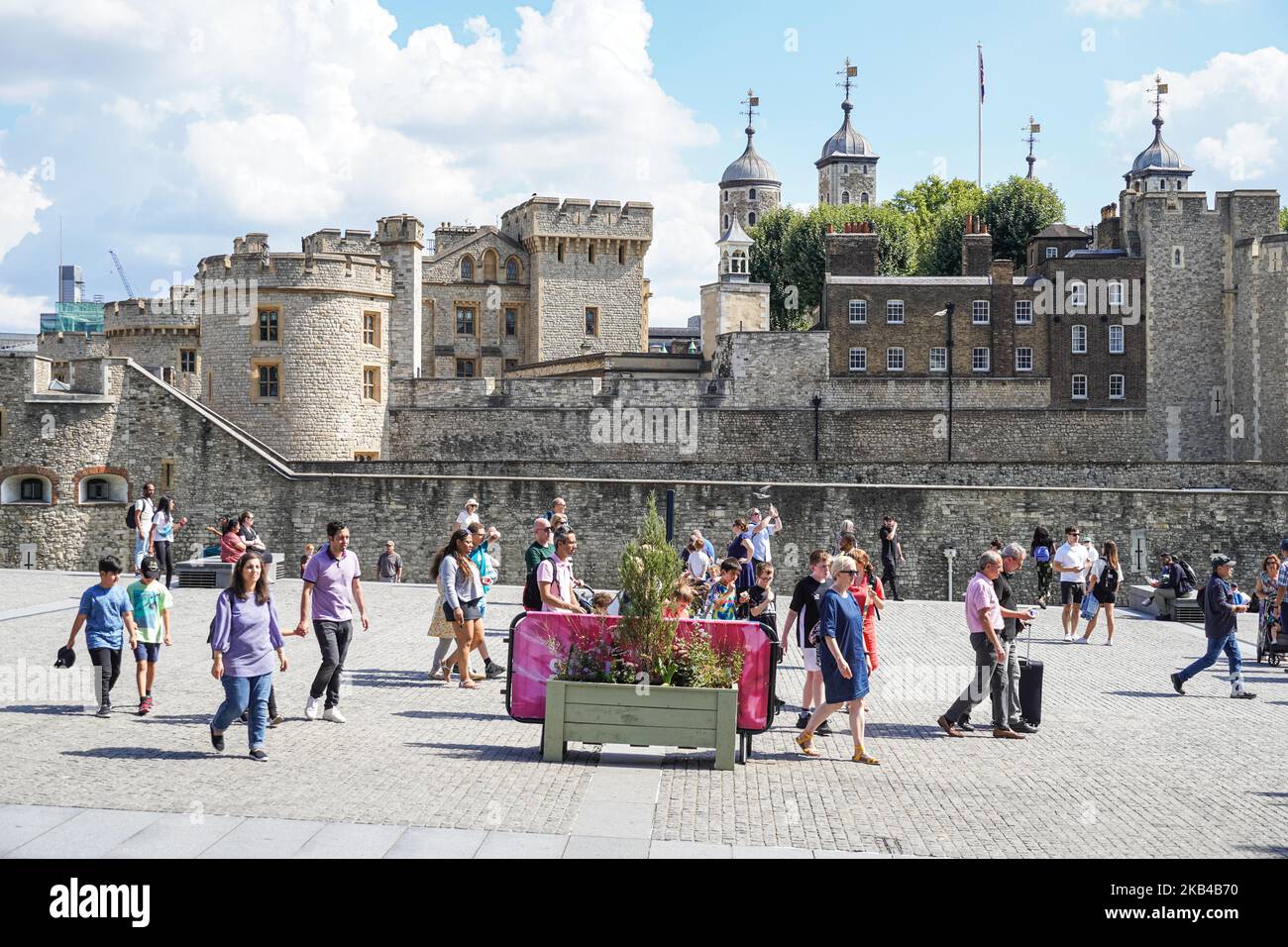 Tourists on Tower Hill walk along the walls of the Tower of London ...
