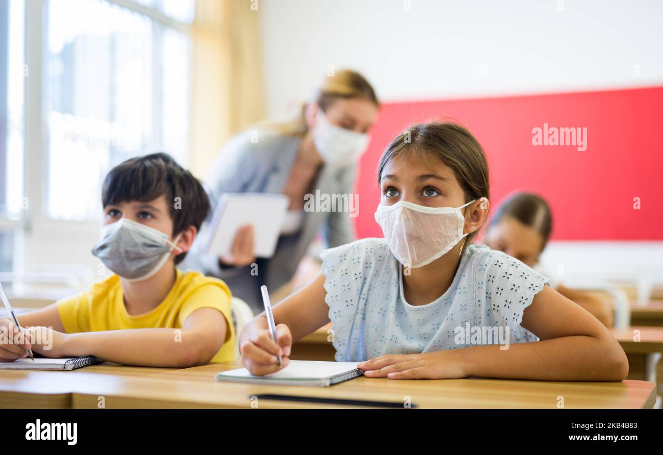 Teacher helping kids to complete exercises Stock Photo - Alamy