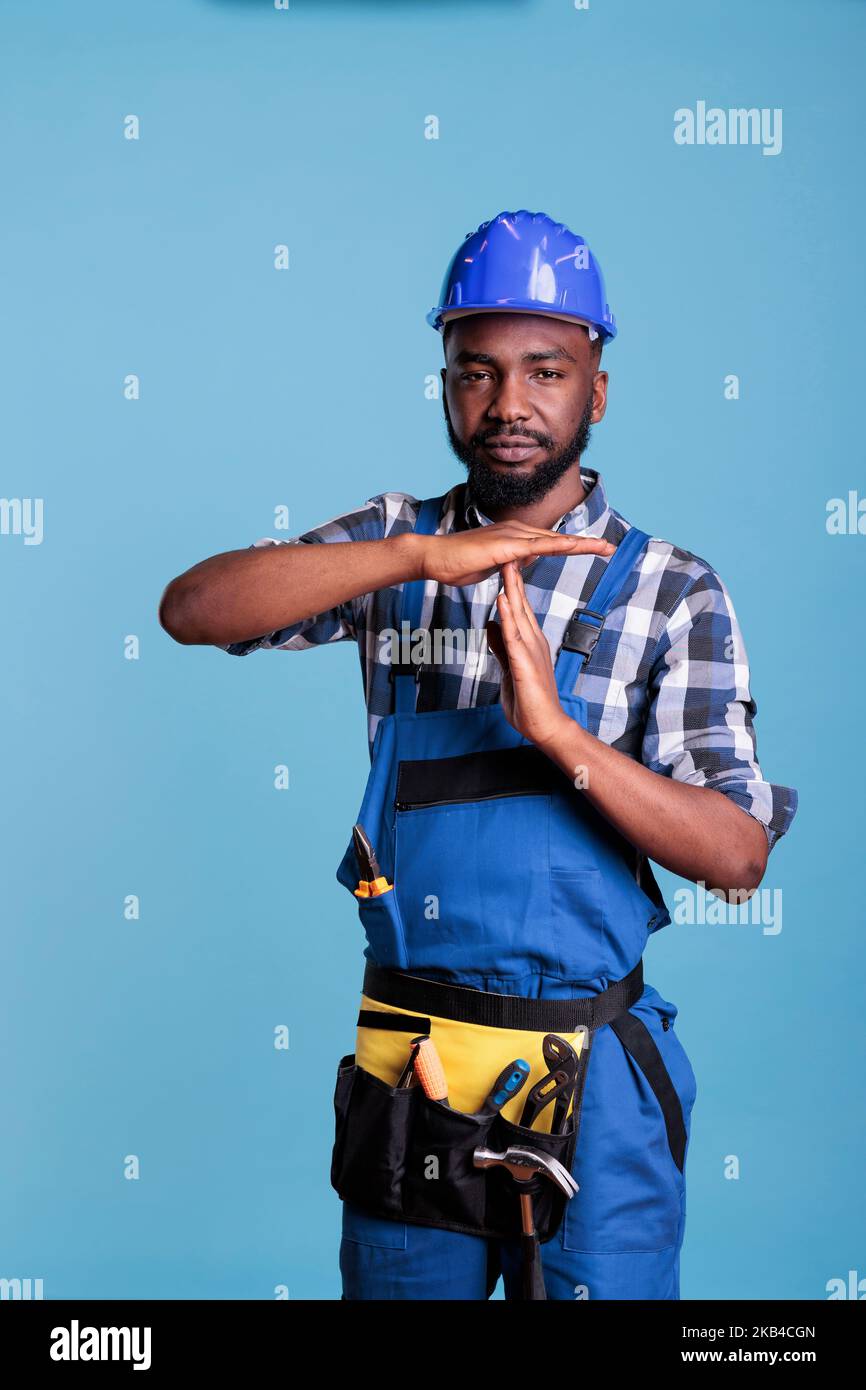 Tired construction worker announcing time-out symbol with hands, making ...