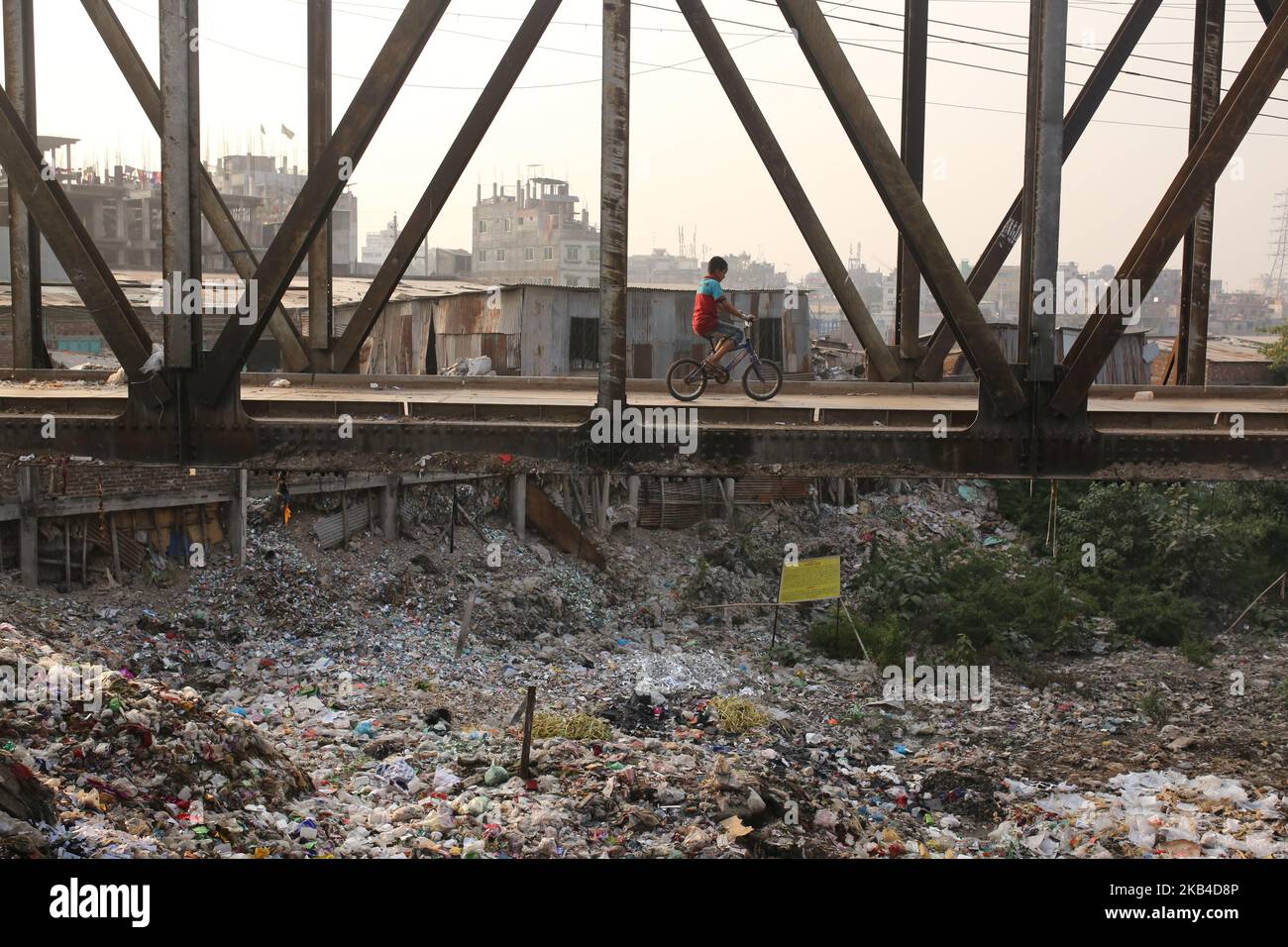A boy drive bicycle on the bridges under plastic garbage-canal that ...