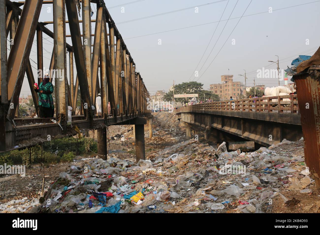 People walk on the bridges under plastic garbage-canal that leads to ...