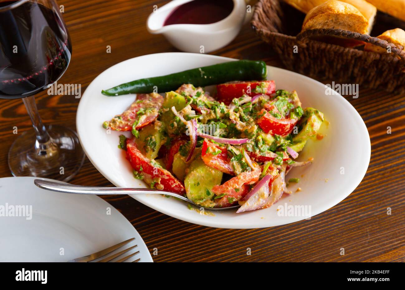 Georgian salad with fresh vegetables, greens and walnuts dressing Stock ...