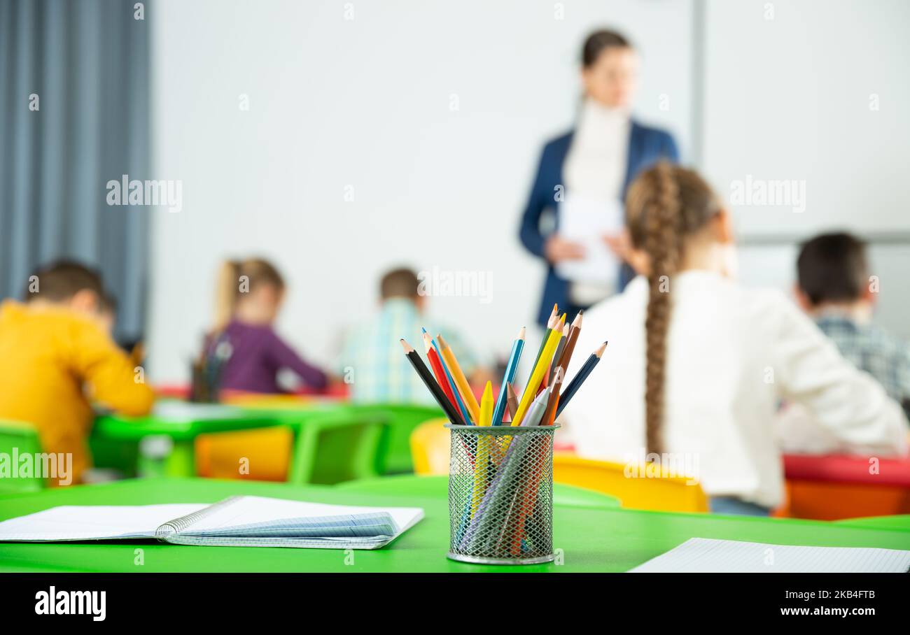 Stand with colored pencils and notebooks on the desk against the ...