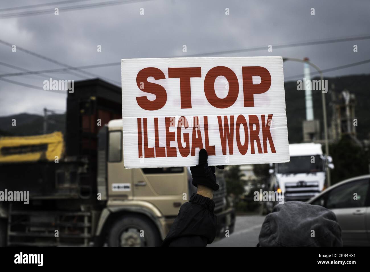 Anti U.S. Base protester holds a placard "STOP Illegal work" during a ...