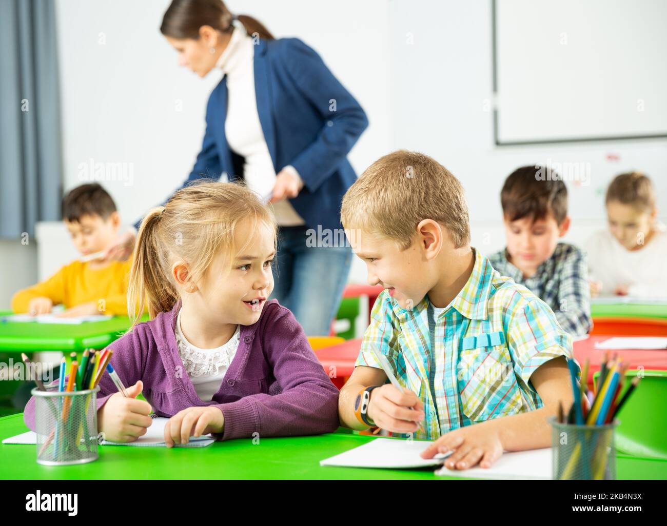 Happy schoolchildren chatting during lesson Stock Photo - Alamy
